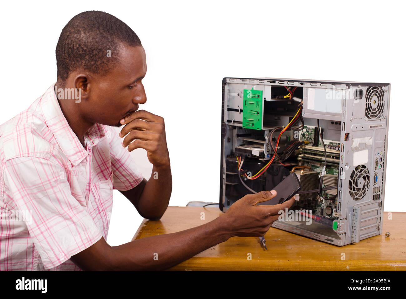 young technician sitting thinking with a desktop computer in front of ...