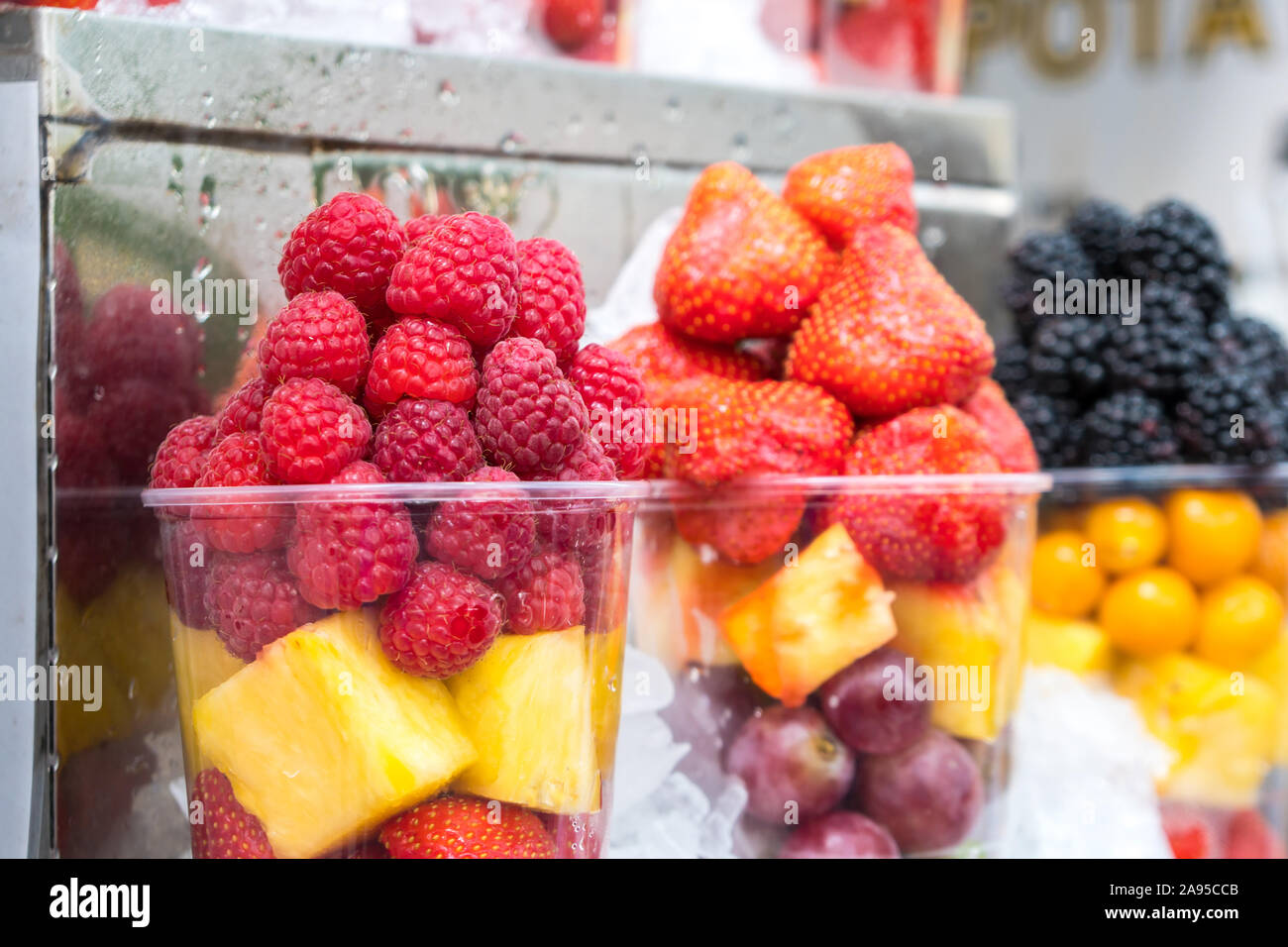 Counter with plastic containers and cups filled of fresh berries ...