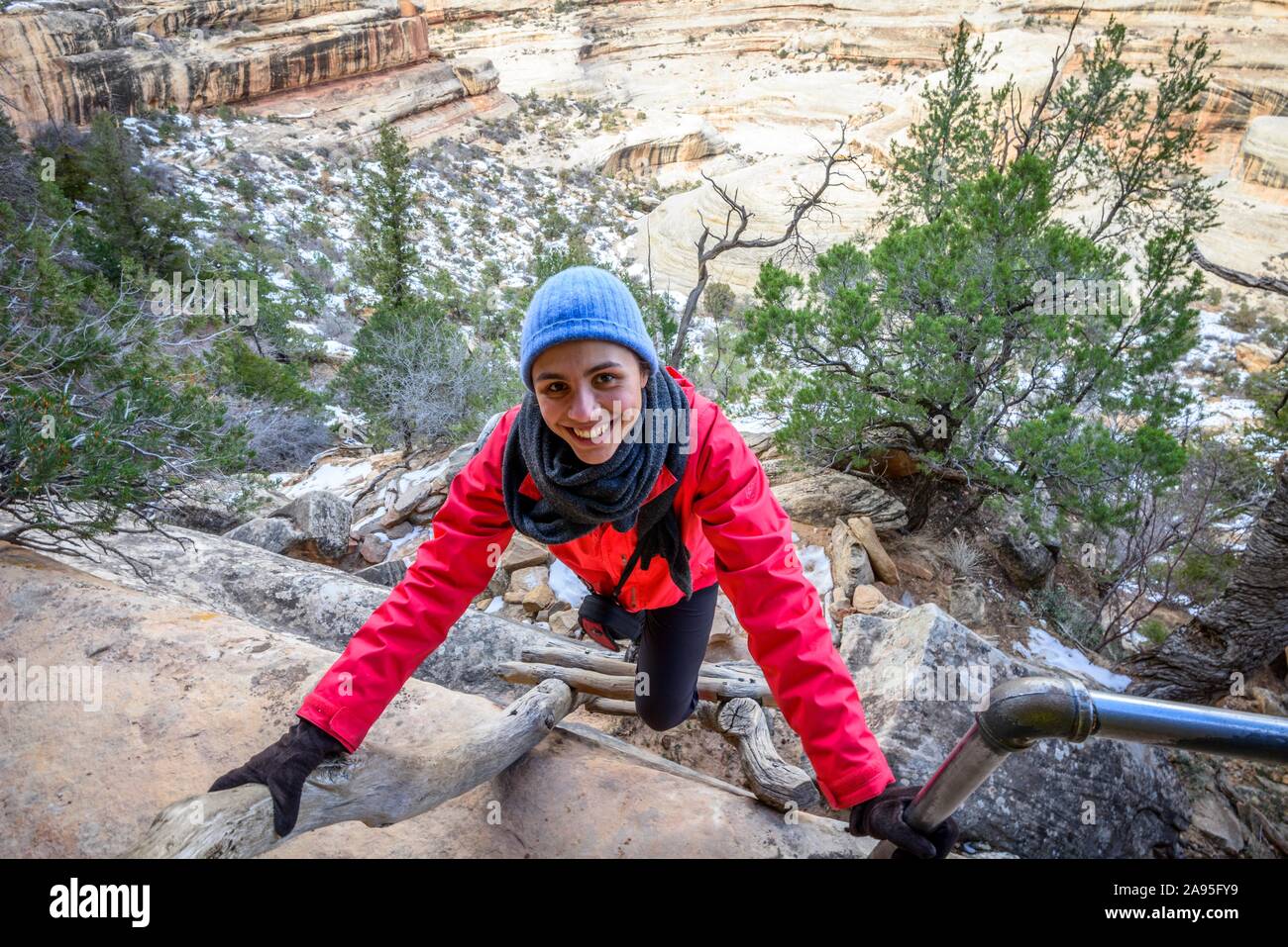 Young woman climbing ladder, trail descending into canyon to Sipapu ...