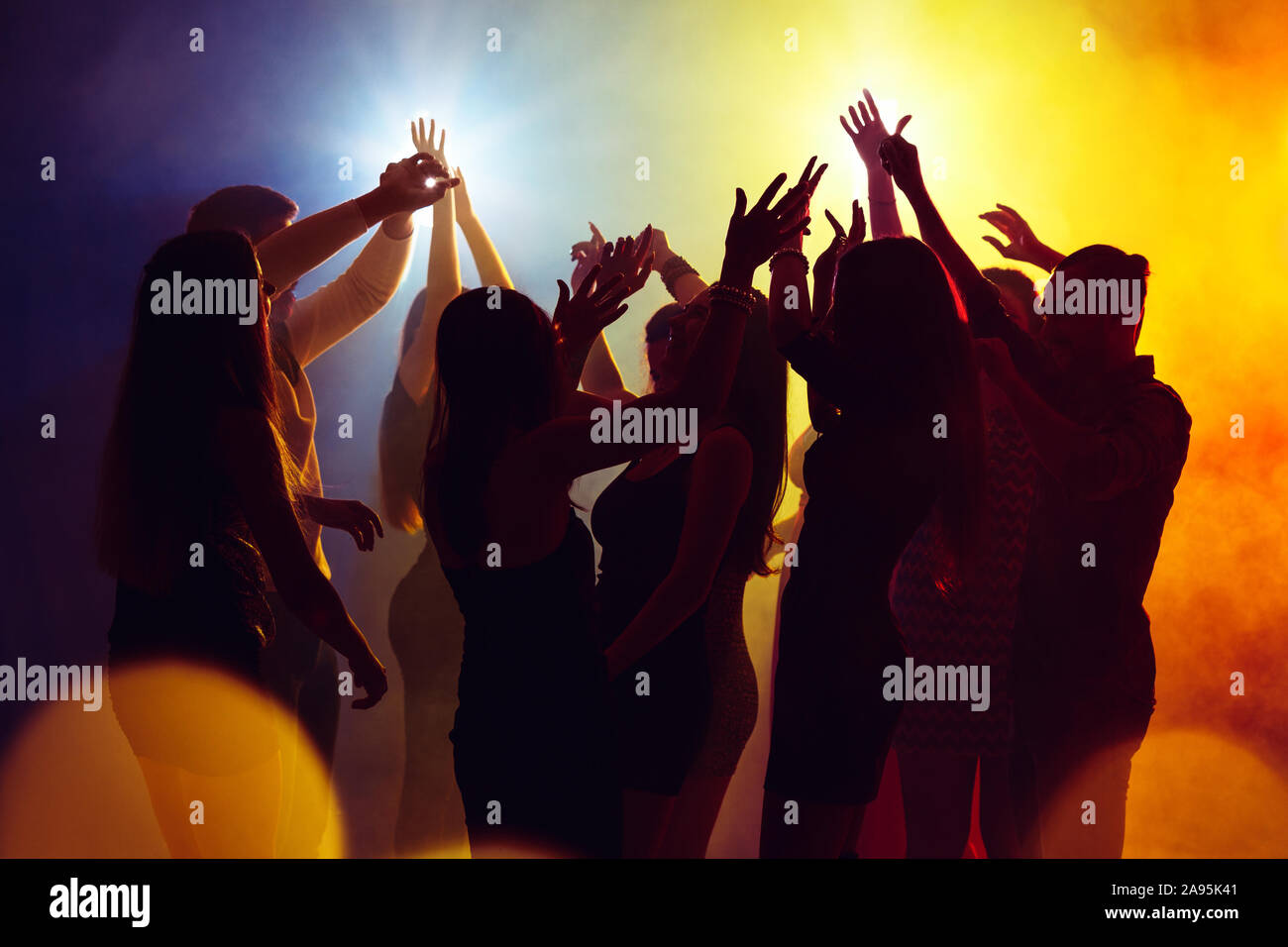 Wild. A crowd of people in silhouette raises their hands on dancefloor ...