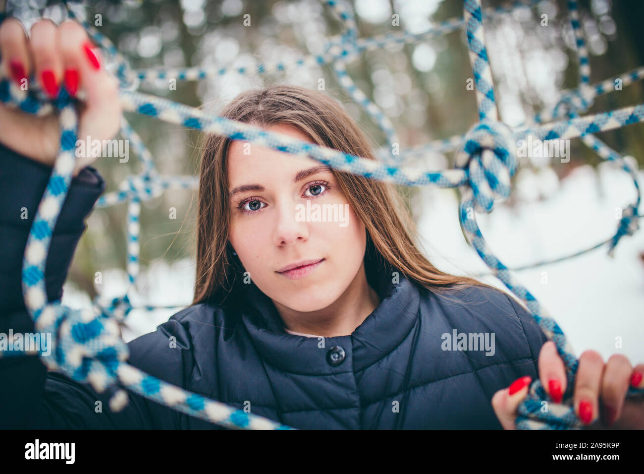 The face of an attractive young brown-haired woman through a rope net ...