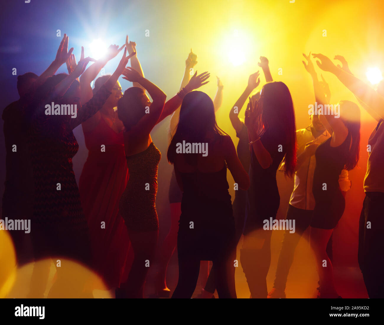 Brightness. A crowd of people in silhouette raises their hands on ...