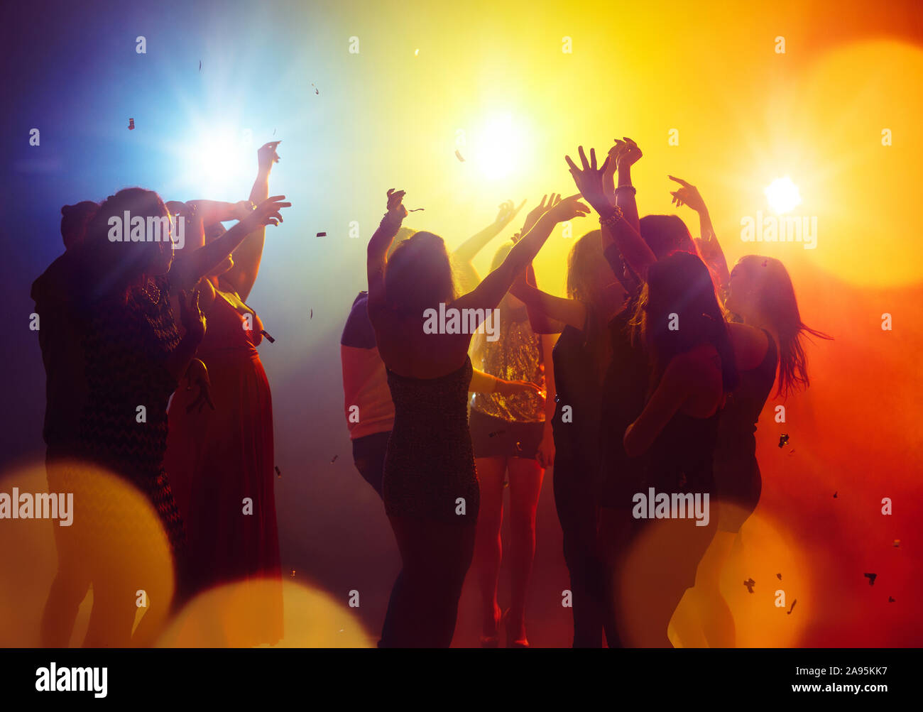 Weekend. A crowd of people in silhouette raises their hands on ...