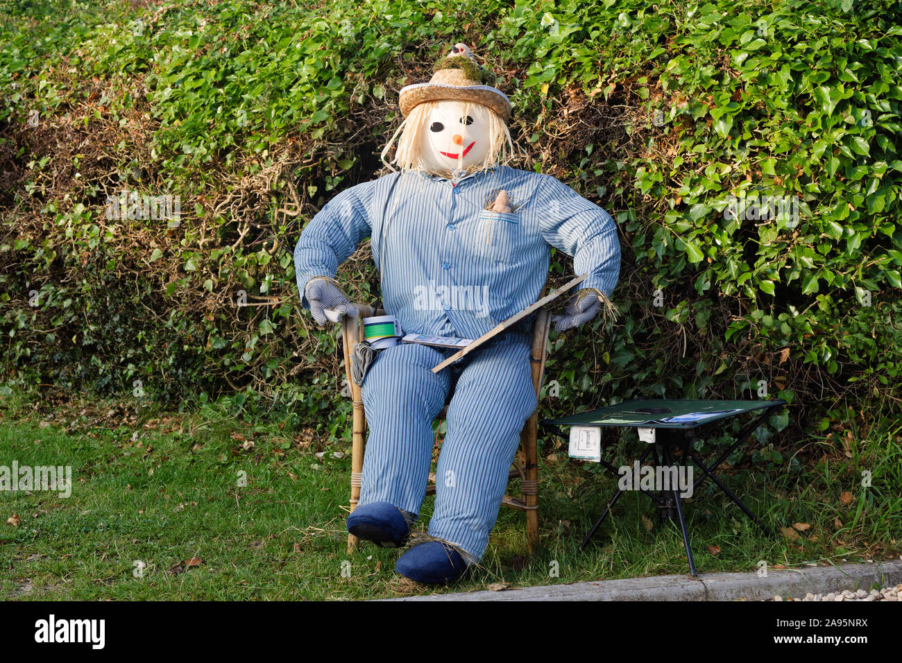 A friendly scarecrow sitting on a chair wearing pyjamas and a straw hat ...
