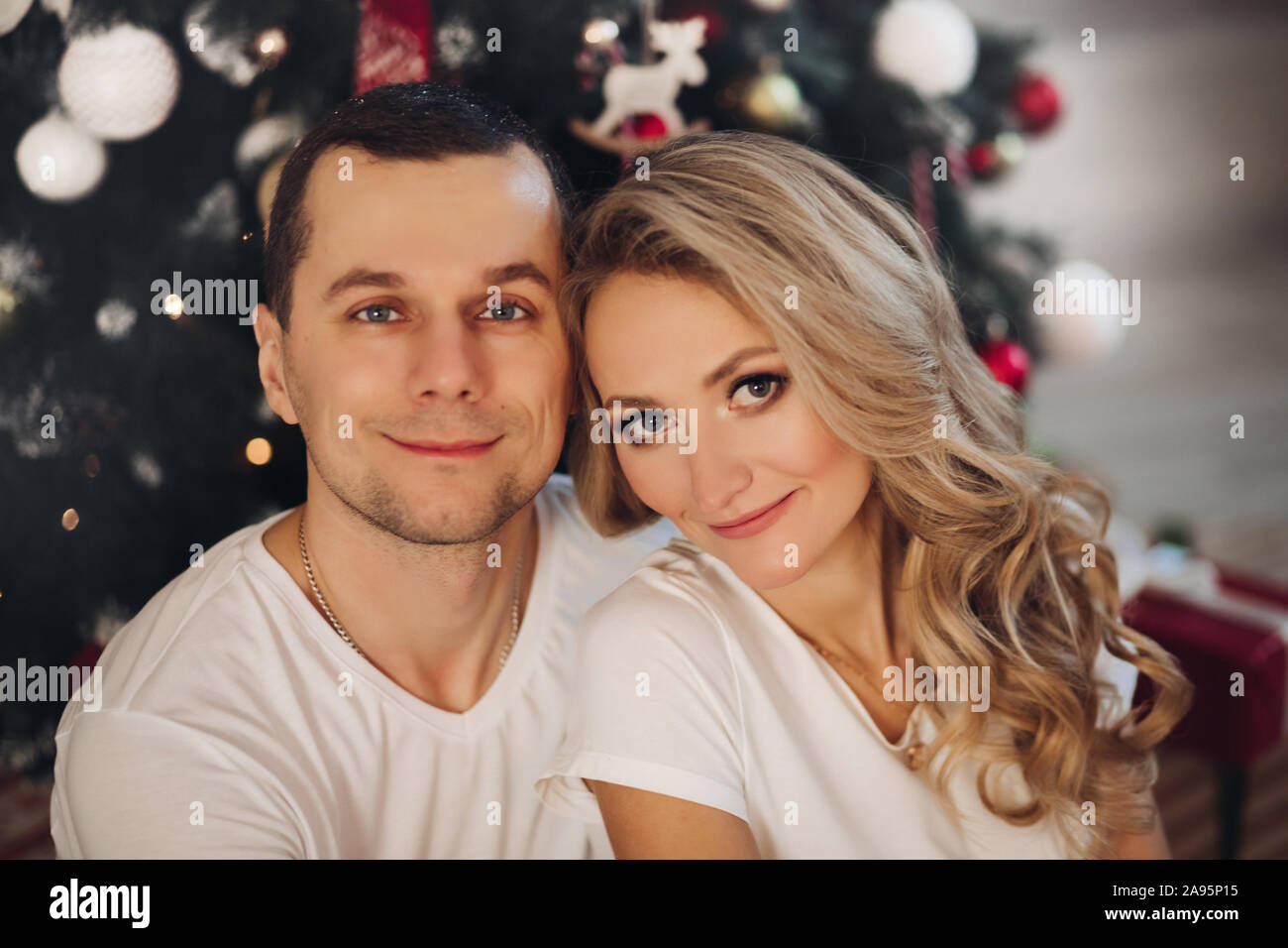 Loving boyfriend kissing girlfriend near Christmas tree Stock Photo - Alamy