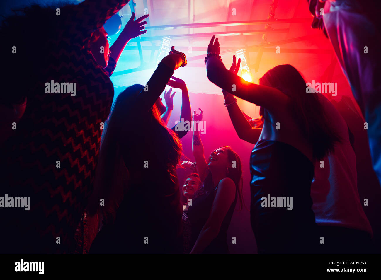 Upcoming. A crowd of people in silhouette raises their hands on ...