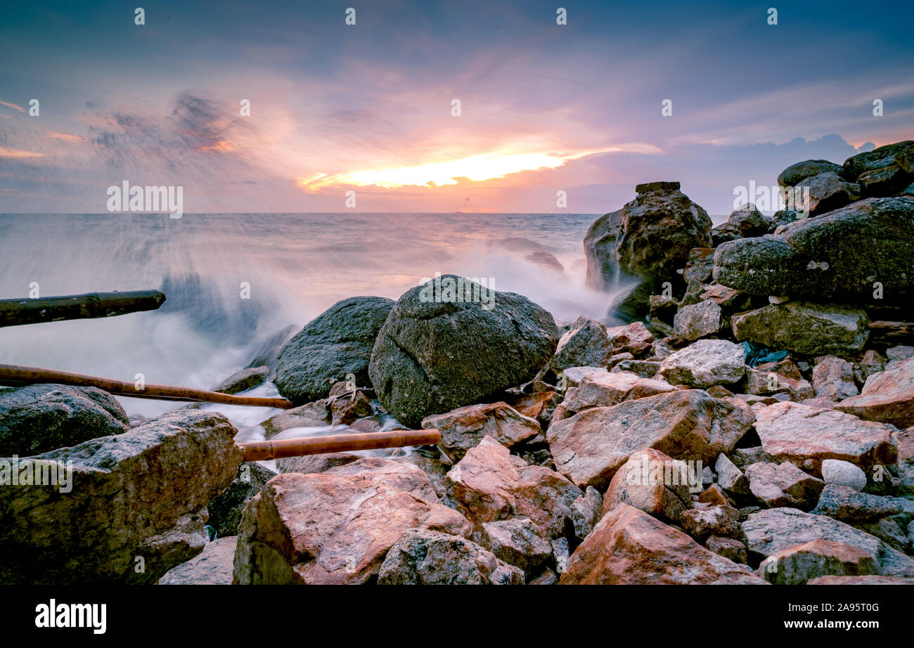 Ocean water splash on rock beach with beautiful sunset sky and clouds ...