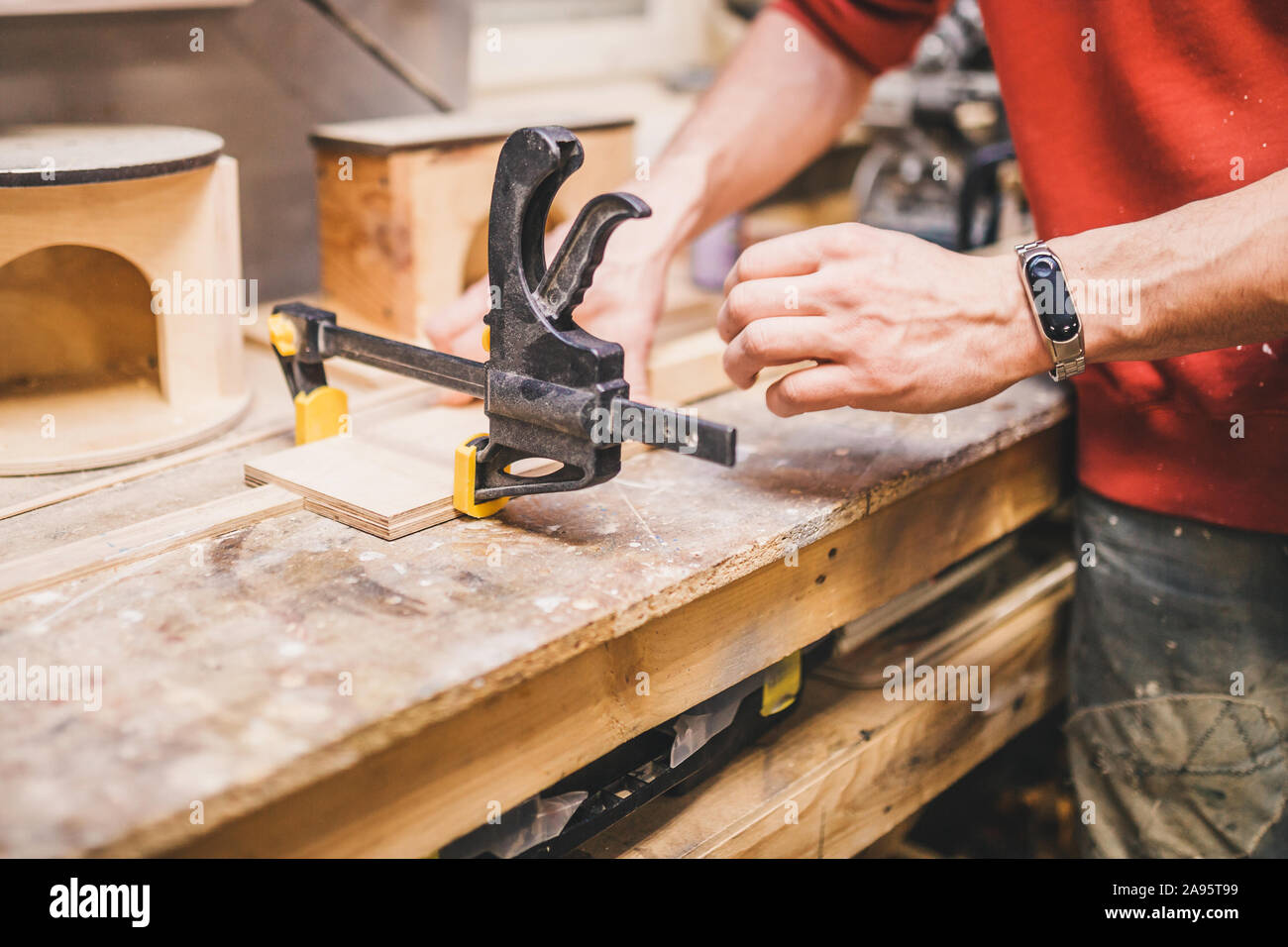 Carpentry workshop - a man fixes wooden parts with glued clamps Stock ...
