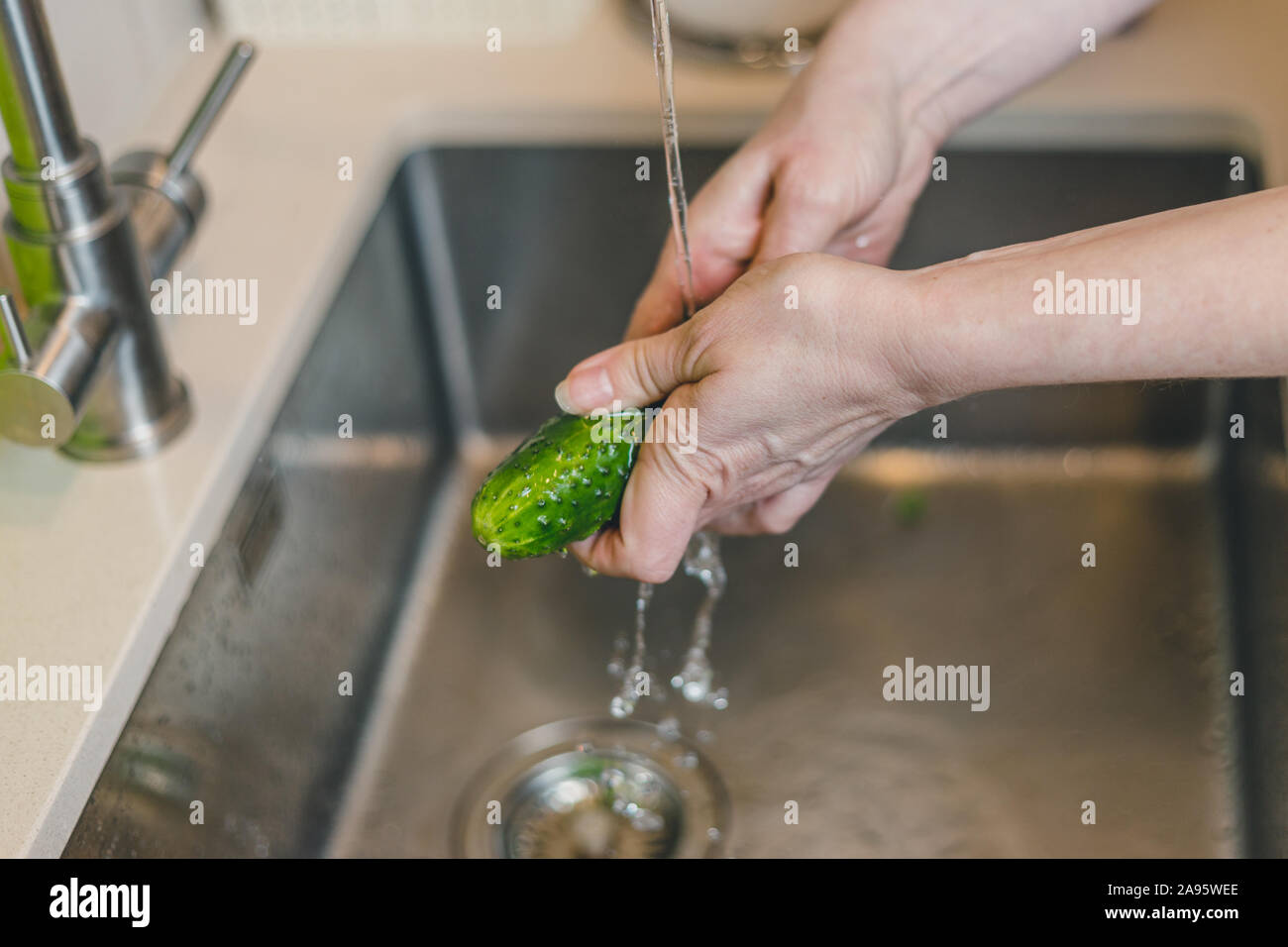 Female hands washing cucumber in the kitchen sink Stock Photo - Alamy