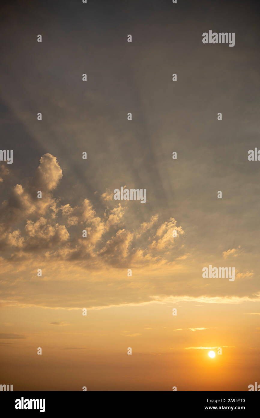 Sun low in the sky under light clouds Stock Photo - Alamy