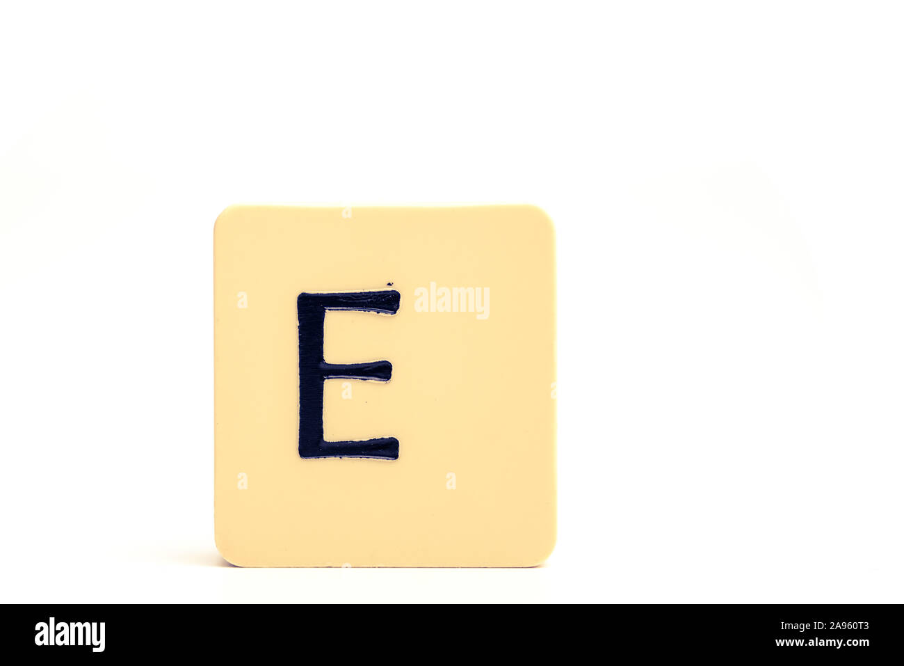 Dark letter E on a pale yellow square block isolated on white ...