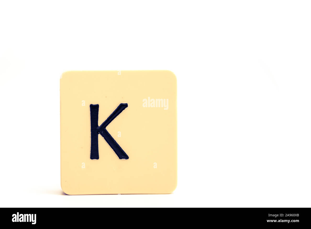 Dark letter K on a pale yellow square block isolated on white ...