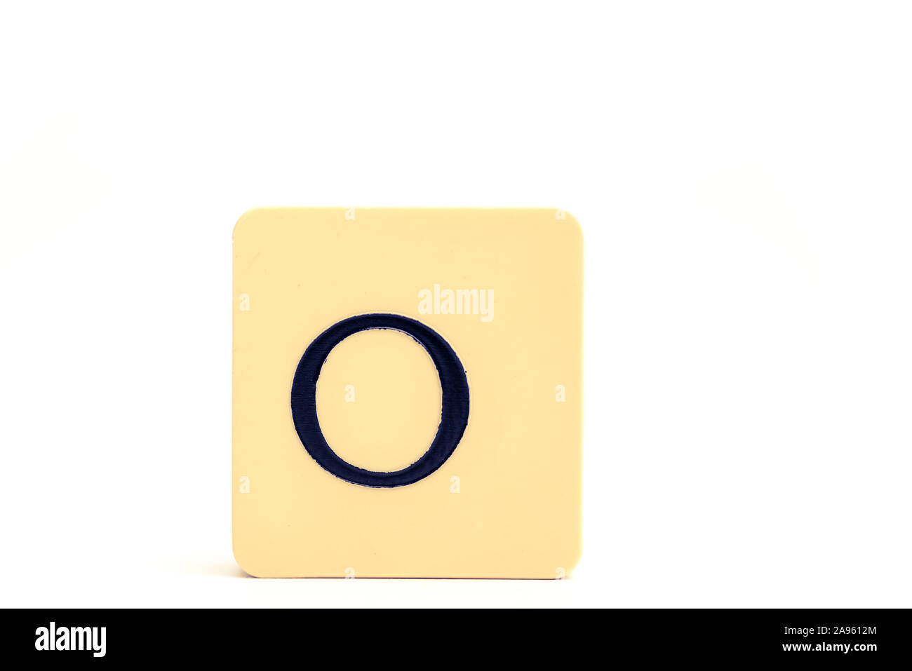 Dark letter O on a pale yellow square block isolated on white ...