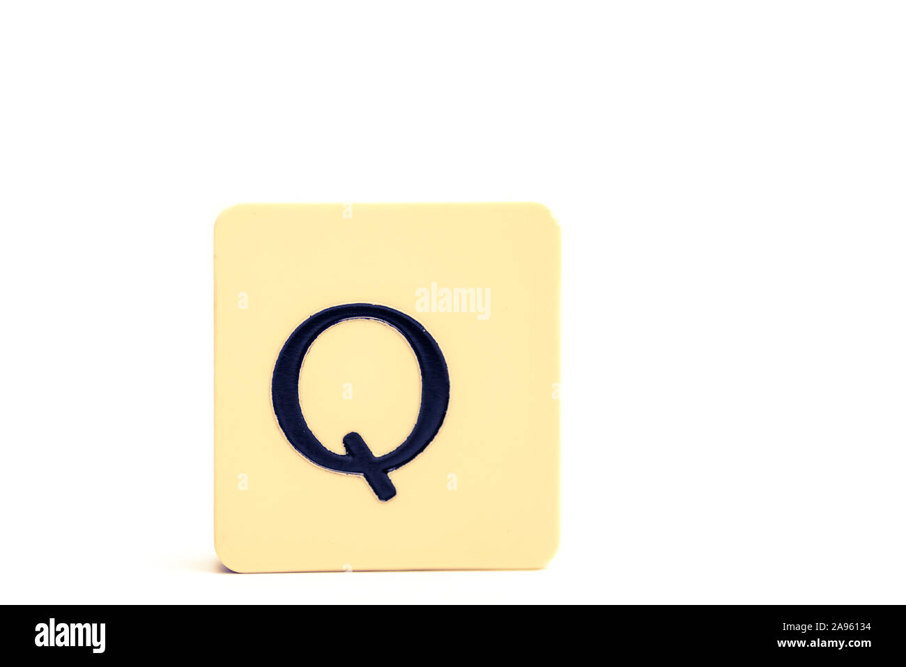Dark letter Q on a pale yellow square block isolated on white ...