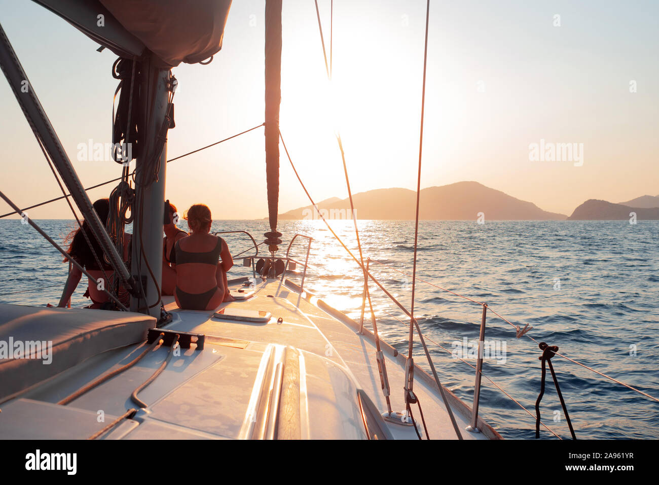 Girls sit on the deck of the yacht and enjoy the sunset. Boat trip on a ...