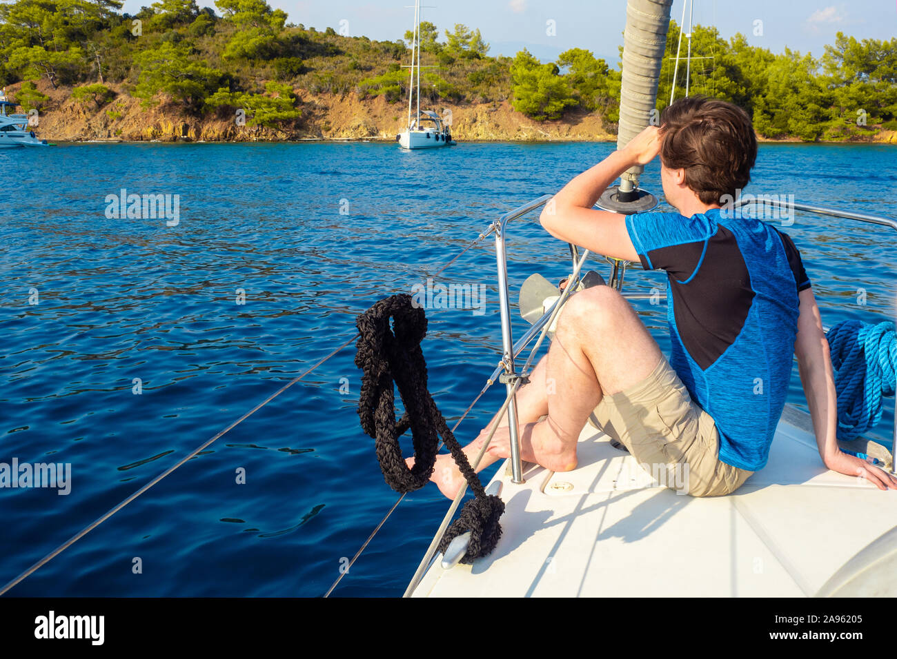 Rest on the sea, boat trip on a yacht. A young man in blue t-shirt sits ...