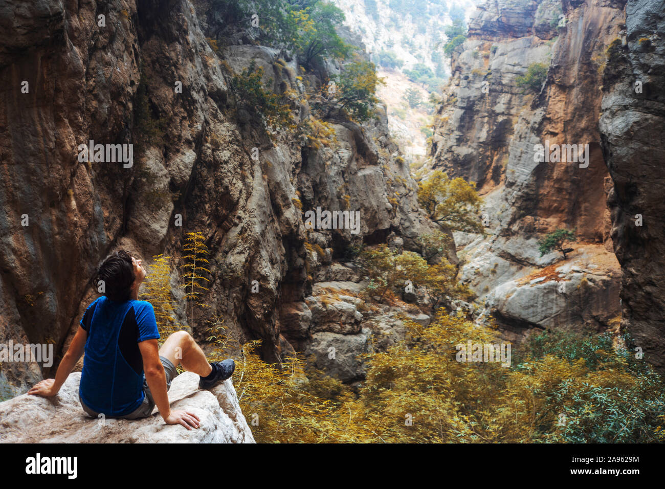A traveler in unity with nature, a young man sits on a rock in a rocky ...