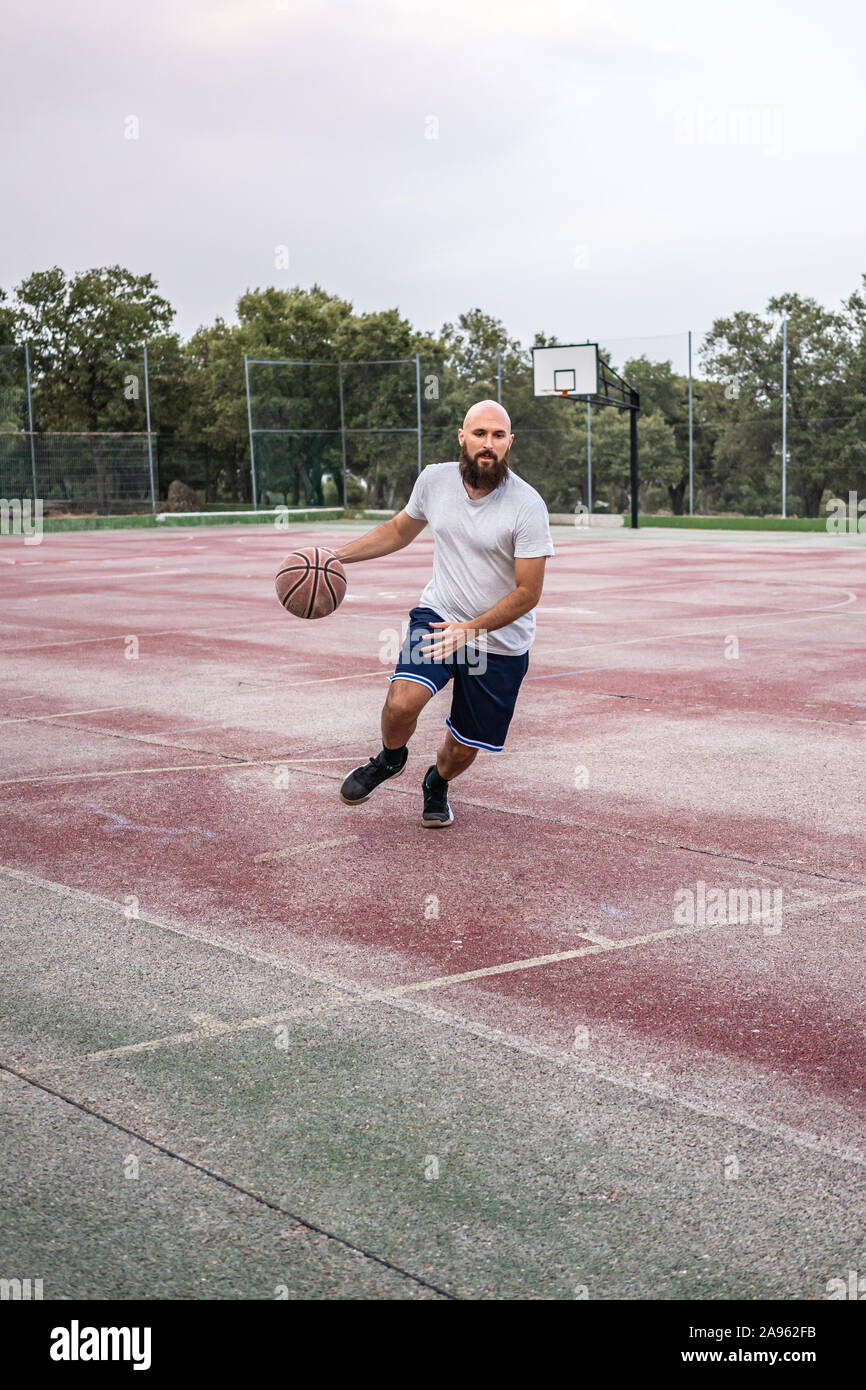 Young basketball player running with the ball on an old basketball ...