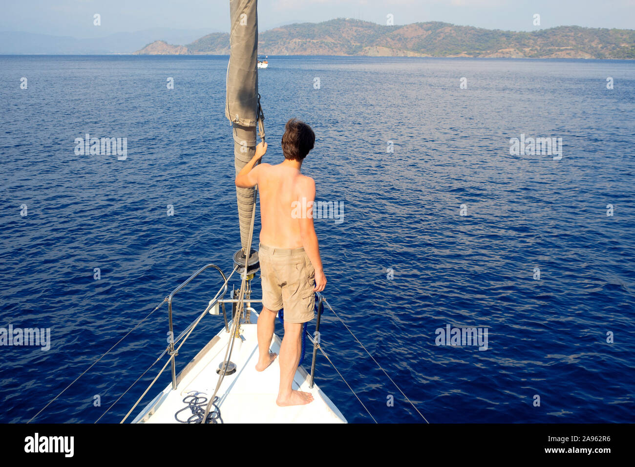 Look beyond the horizon. man in shorts stands on the deck near the sail ...