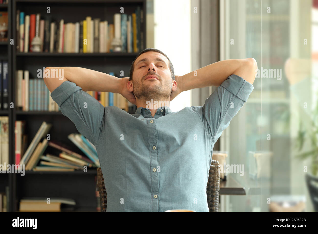 Front view of a relaxed man resting sitting with arms on head sitting ...