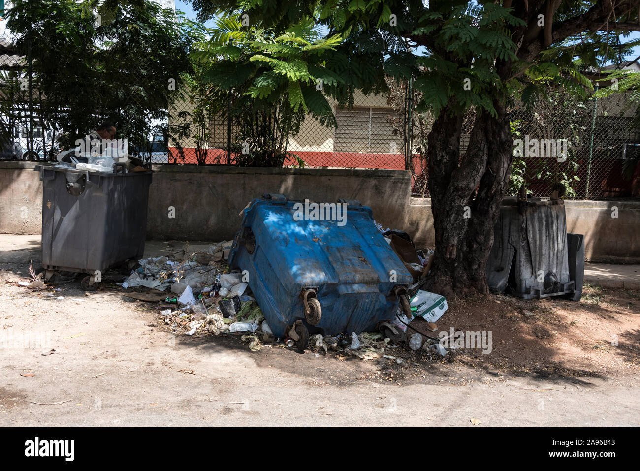 A large industrial wheelie bin tipped over with its piles of rubbish ...