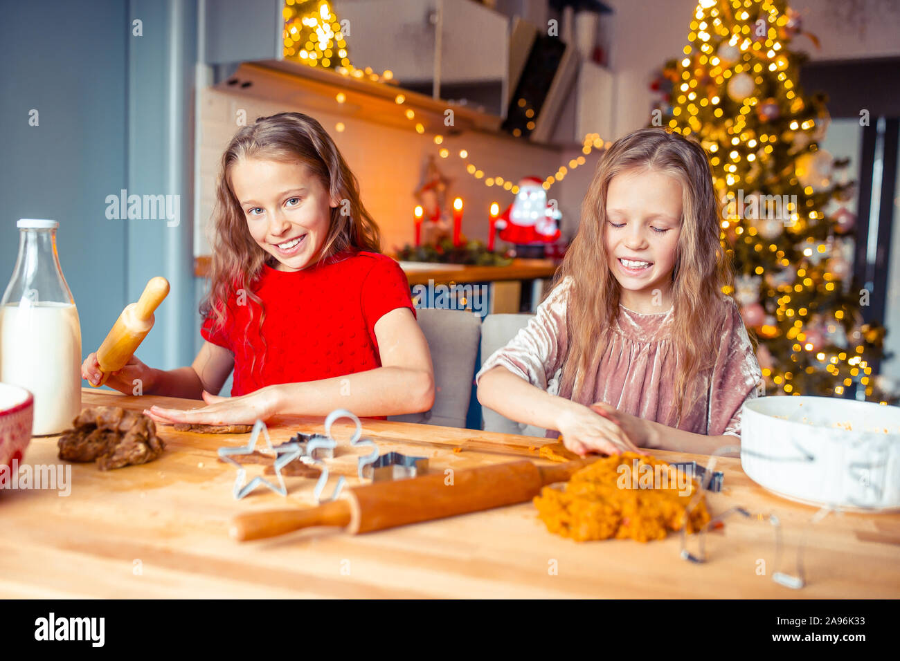 Adorable little girls baking cookies background of lights and Christmas ...
