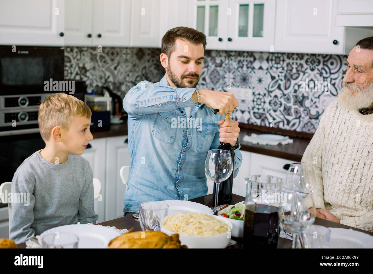 Happy family having holiday dinner. Grandfather, father and little son ...