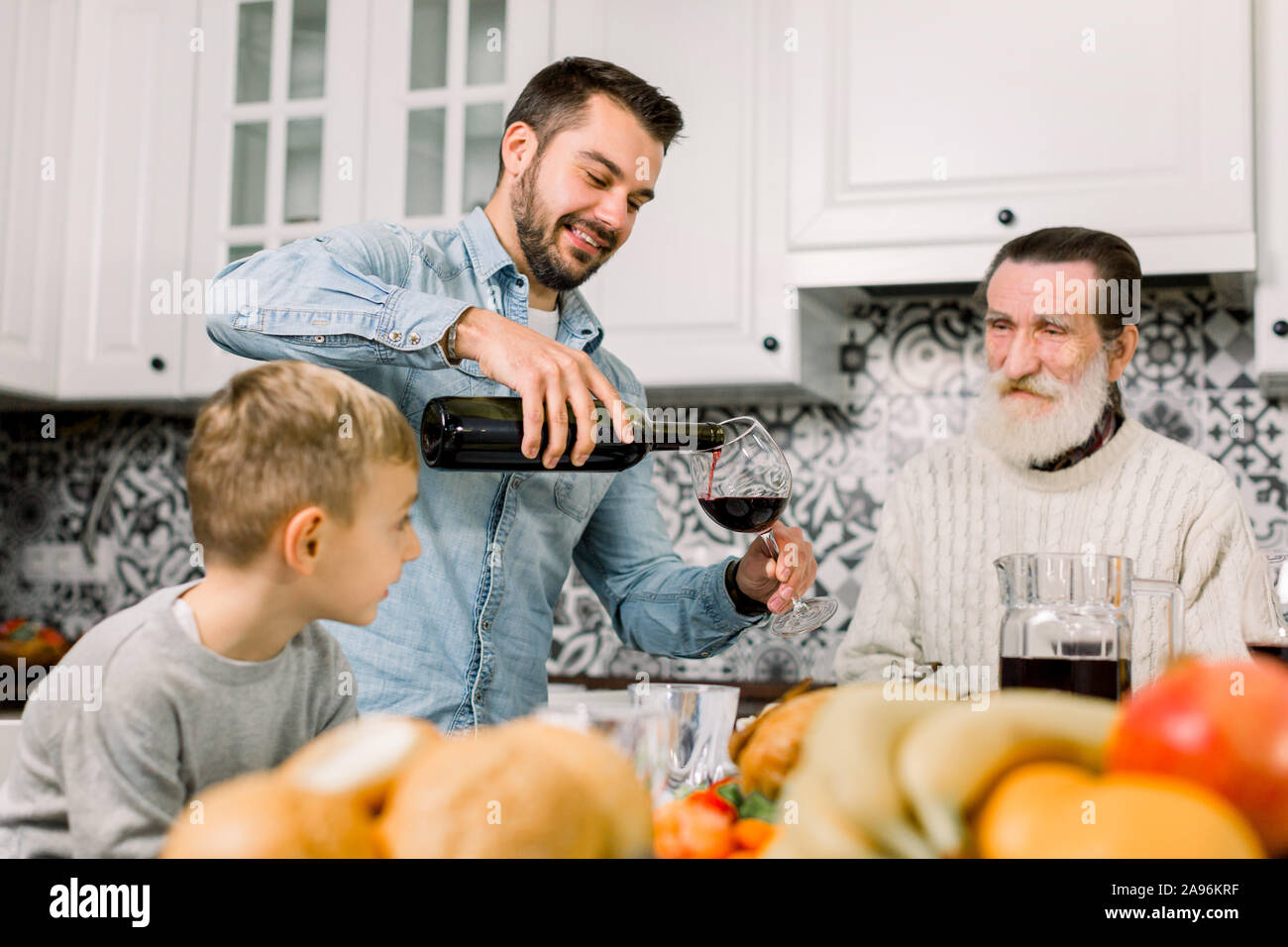 happy smiling father pouring wine into glasses for his family on ...