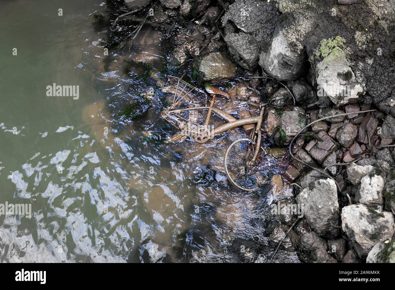 Pollution by dumped bicycles and and other trash at the edge of a river ...