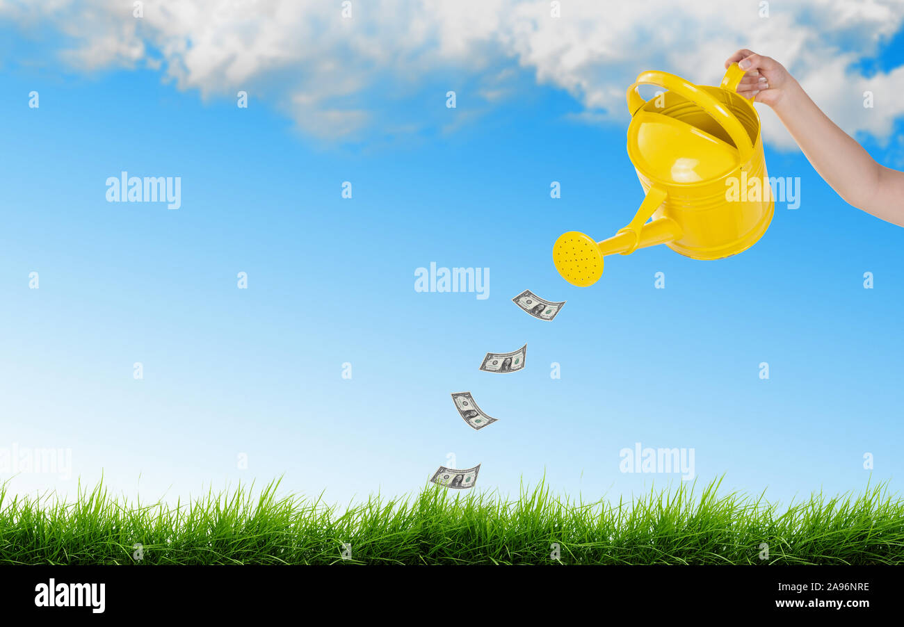 One Dollar Bills are coming out from a yellow watering can holding by a ...