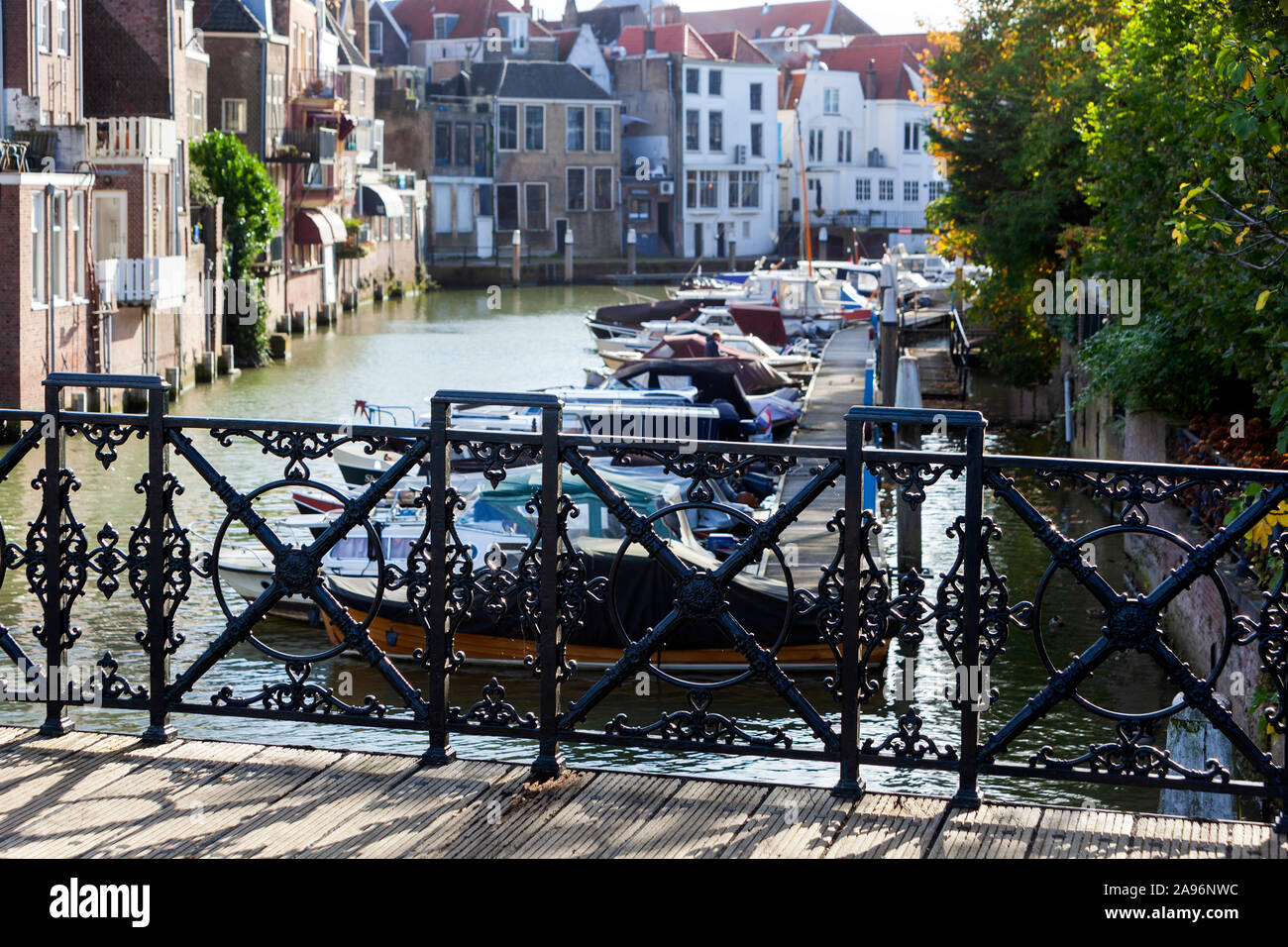 Nostalgia view through a cast iron bridge railing on a harbor and ...