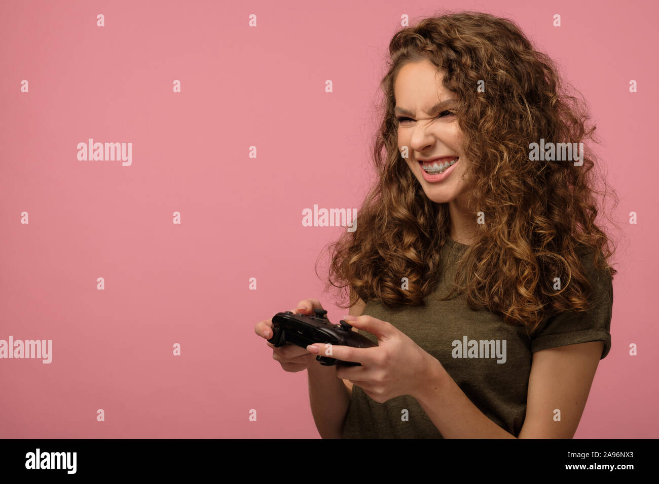 Pretty geek girl with curly hair holding gamepad and playing videogame ...