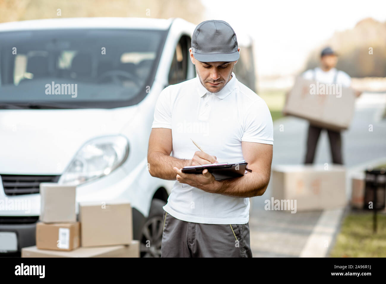 Portrait of delivery man in uniform standing with documents near the ...