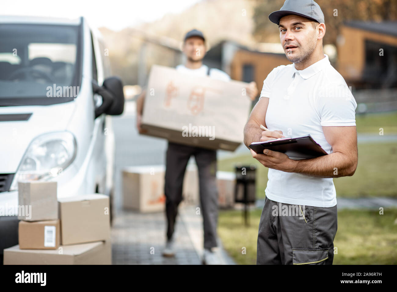 Two male couriers delivering goods by cargo van vehicle, unloading ...