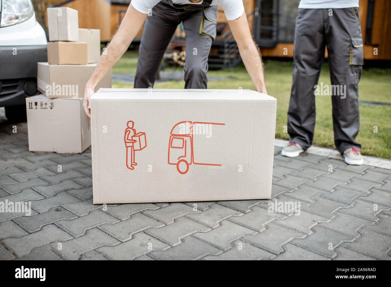 Delivery men moving cardboard boxes outdoors, delivering goods with ...