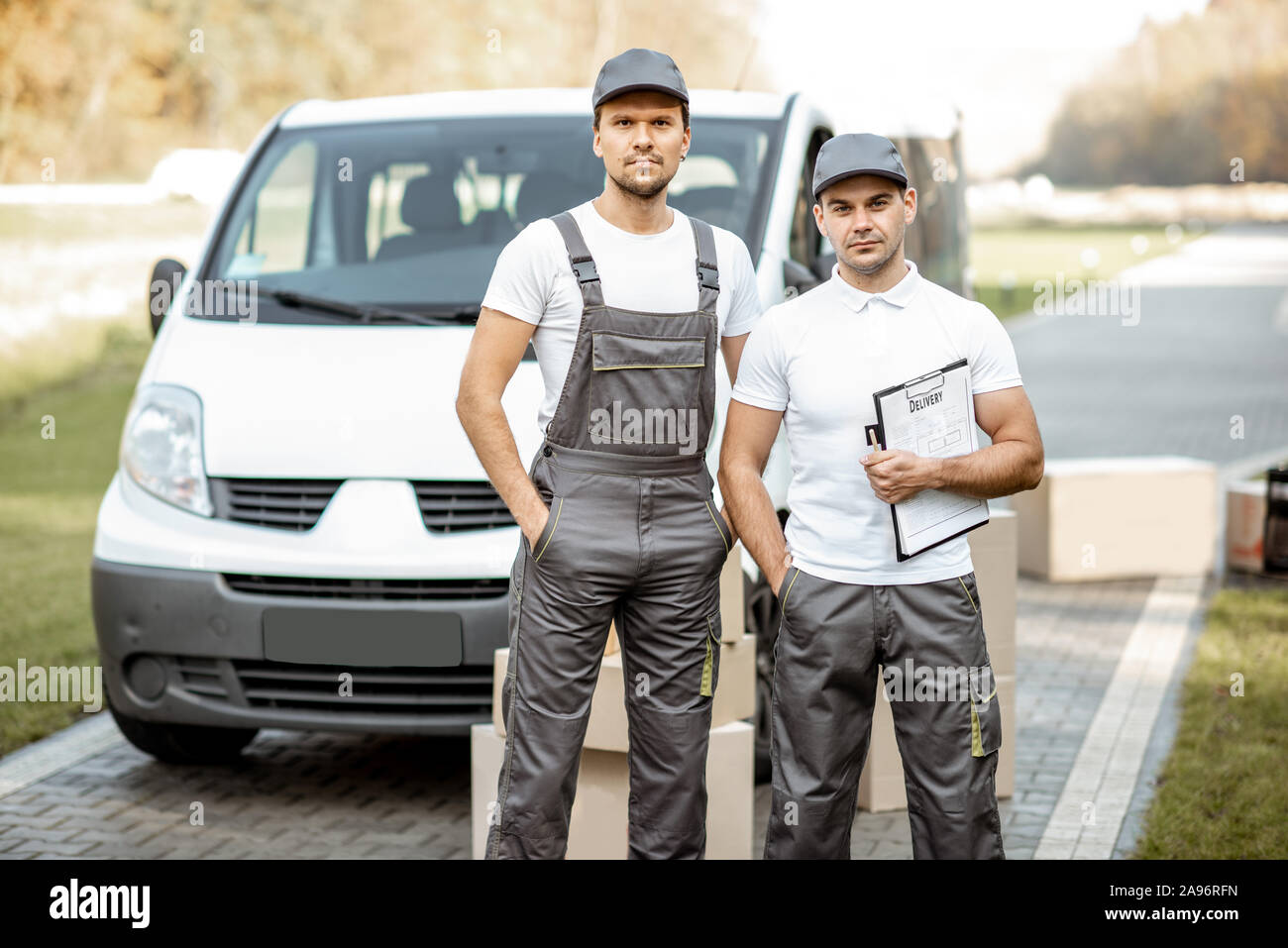 Portrait of a two delivery men in uniform standing together with check ...