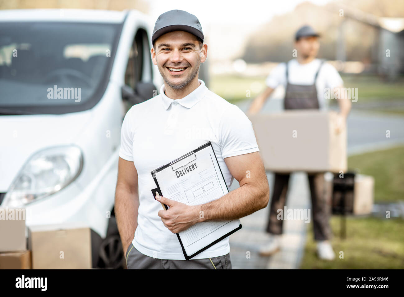 Portrait of delivery man in uniform standing with documents near the ...
