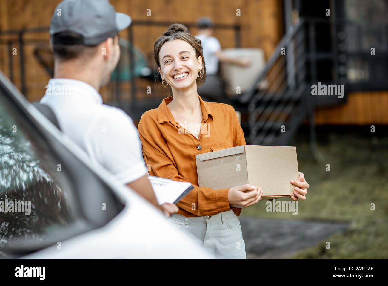 Portrait of a happy client with a male courier delivering goods by ...