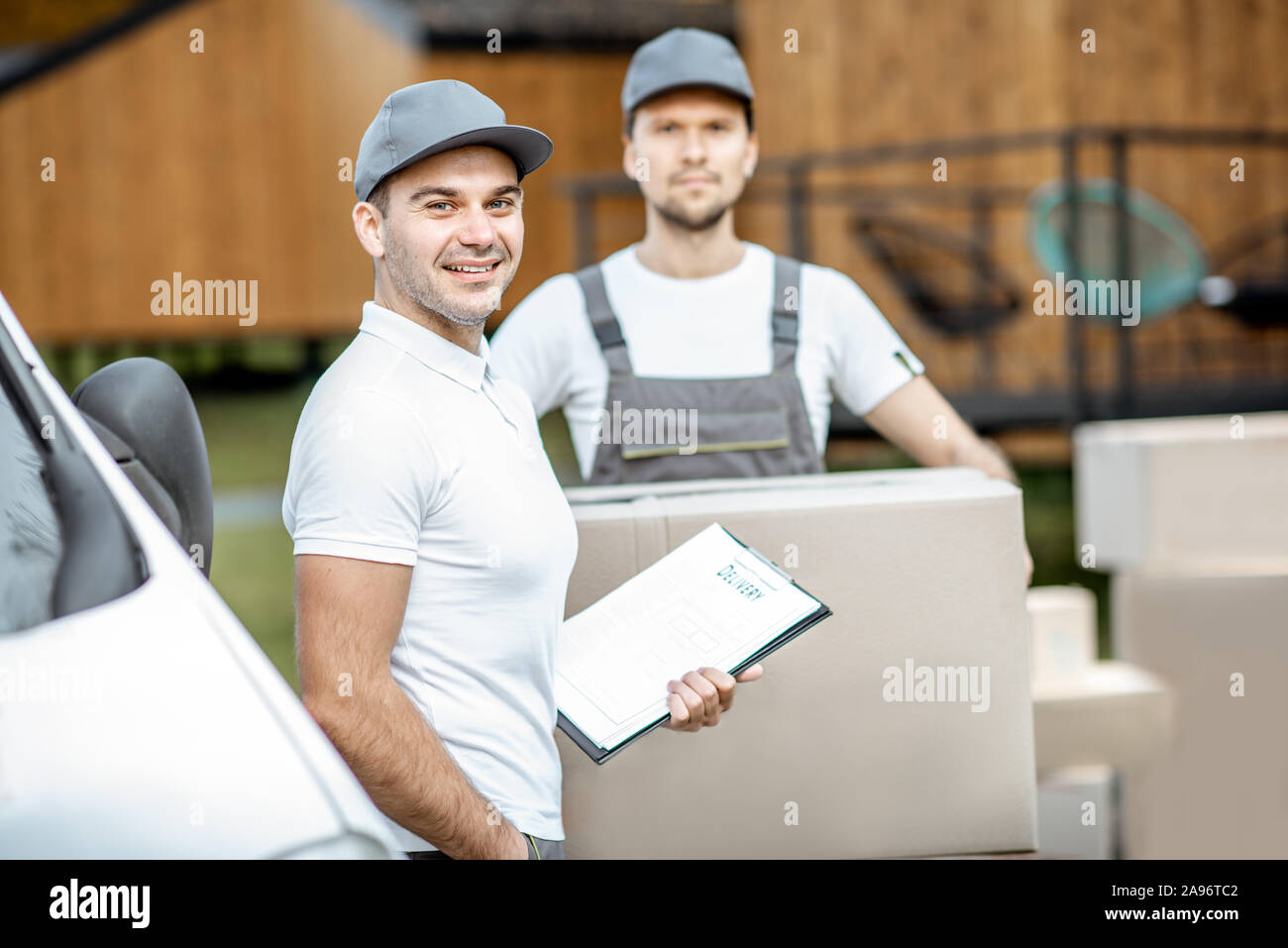 Portrait of a two delivery men in uniform standing together with check ...