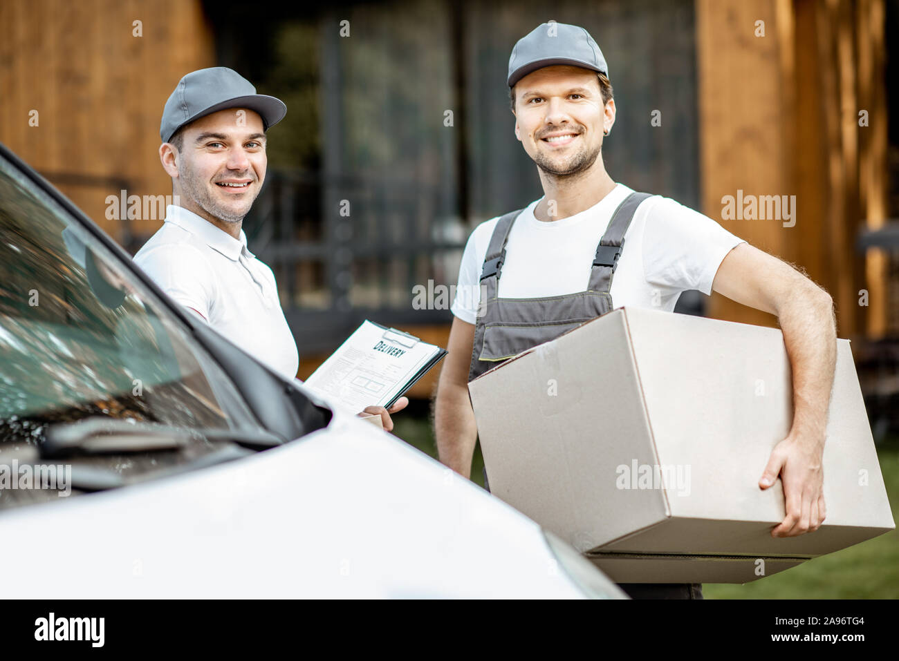 Portrait of a two cheerful delivery men in uniform standing together ...