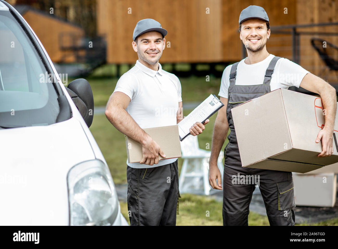 Portrait of a two cheerful delivery men in uniform standing together ...