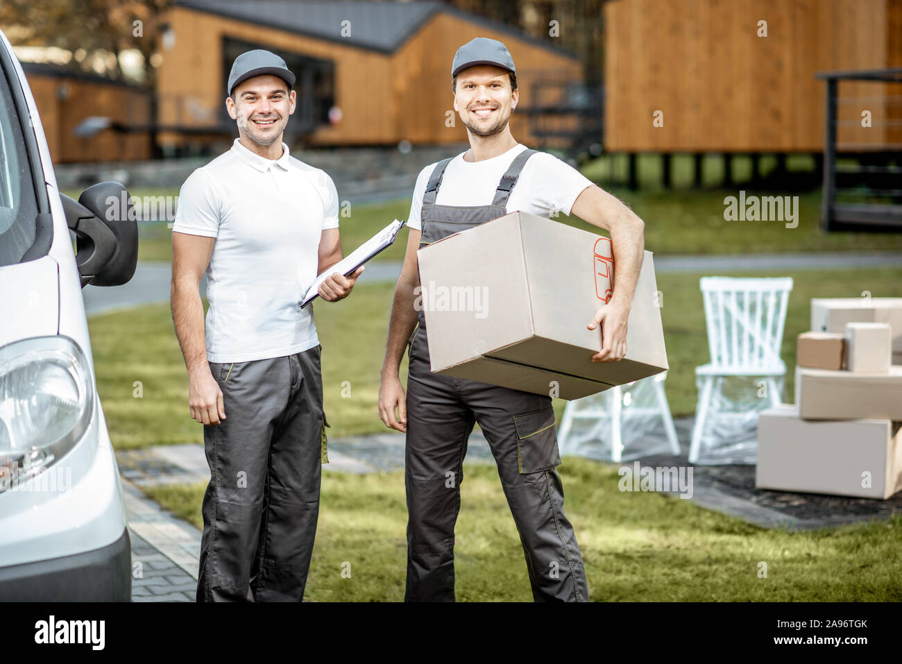 Portrait of a two delivery men in uniform standing together with check ...