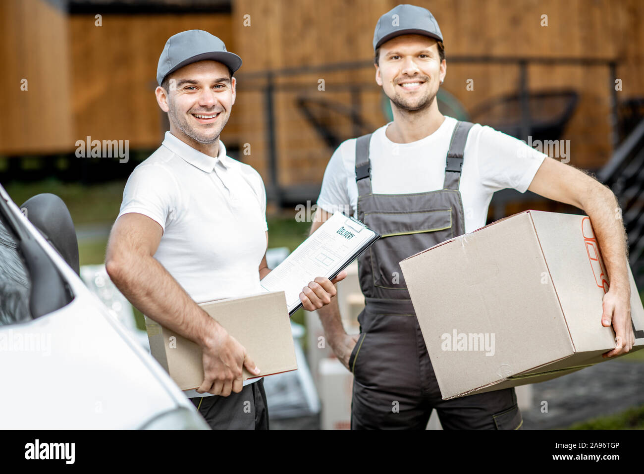 Portrait of a two cheerful delivery men in uniform standing together ...