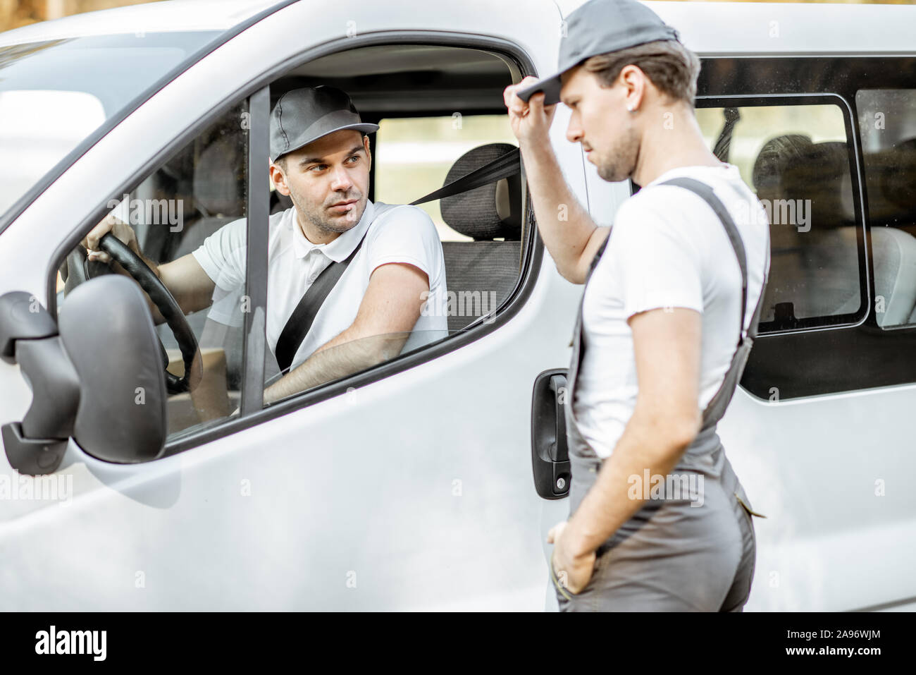 Delivery company employees in uniform delivering goods by cargo van ...