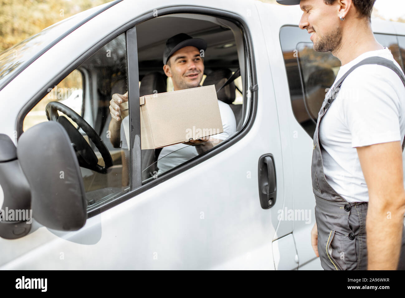 Delivery company employees in uniform delivering goods by cargo van ...