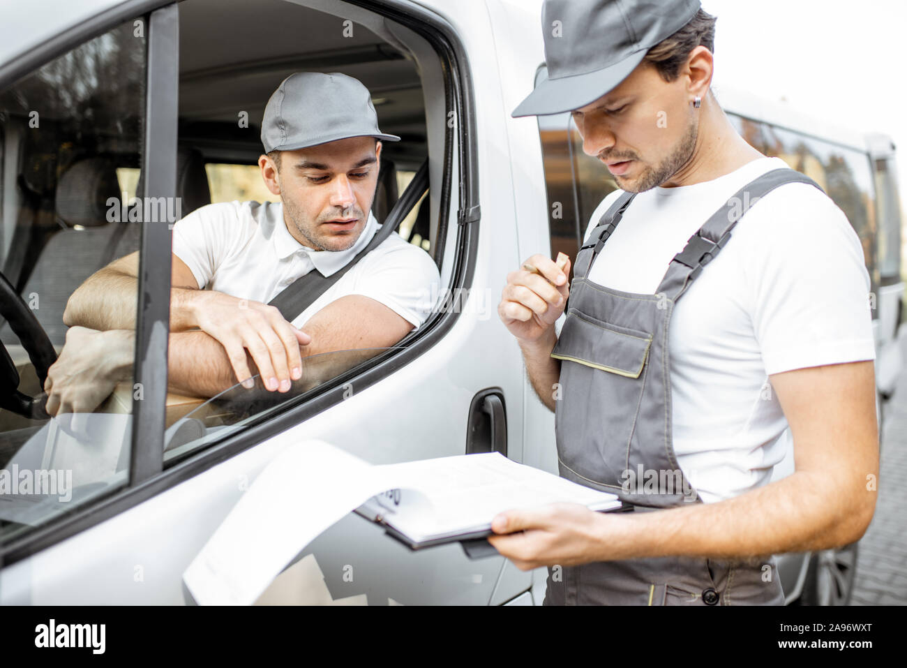 Delivery company employees in uniform delivering goods by cargo van ...