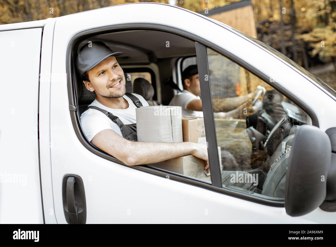 Cheerful delivery company employees in uniform driving cargo vehicle ...