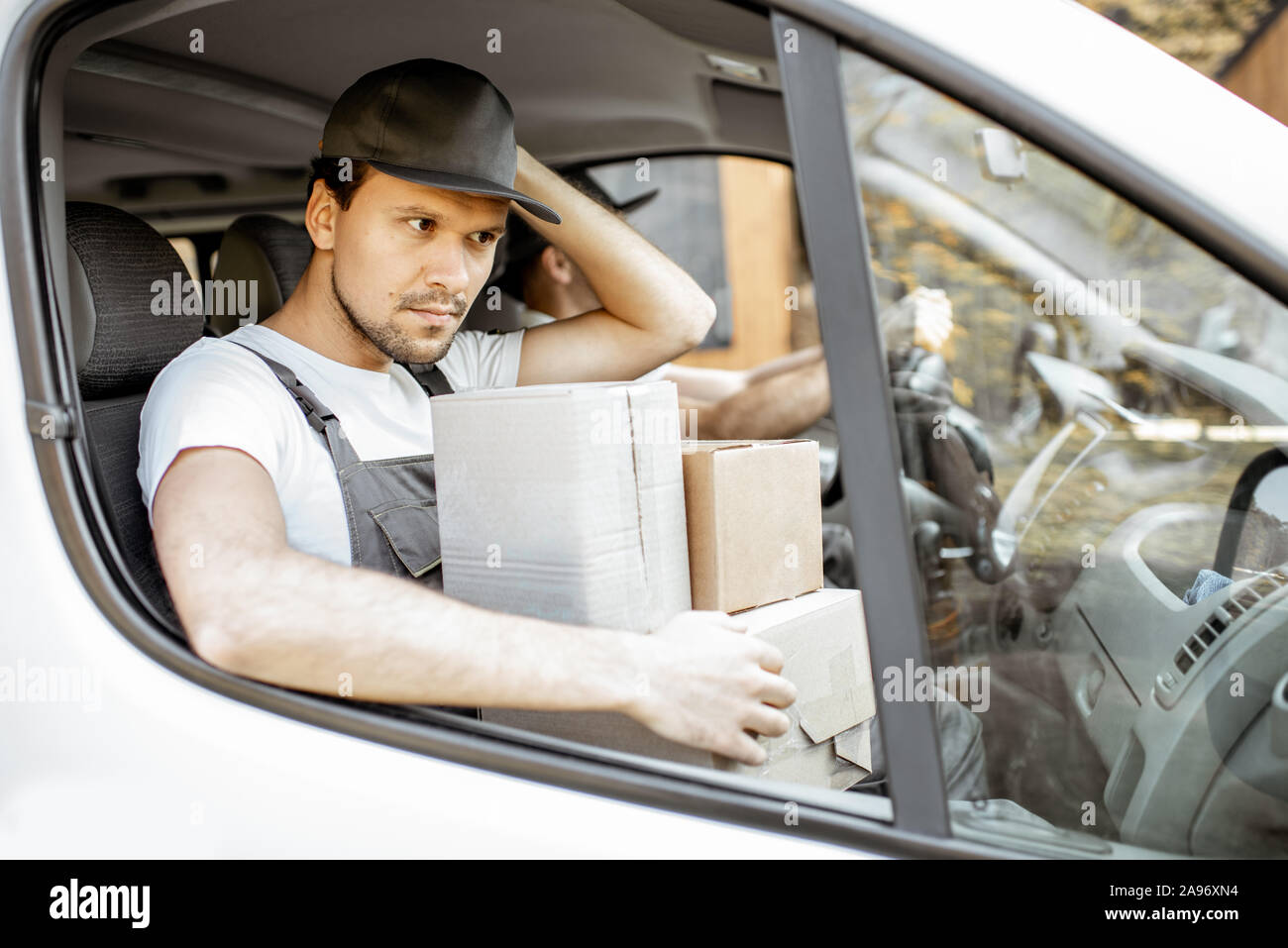 Cheerful delivery company employees in uniform driving cargo vehicle ...