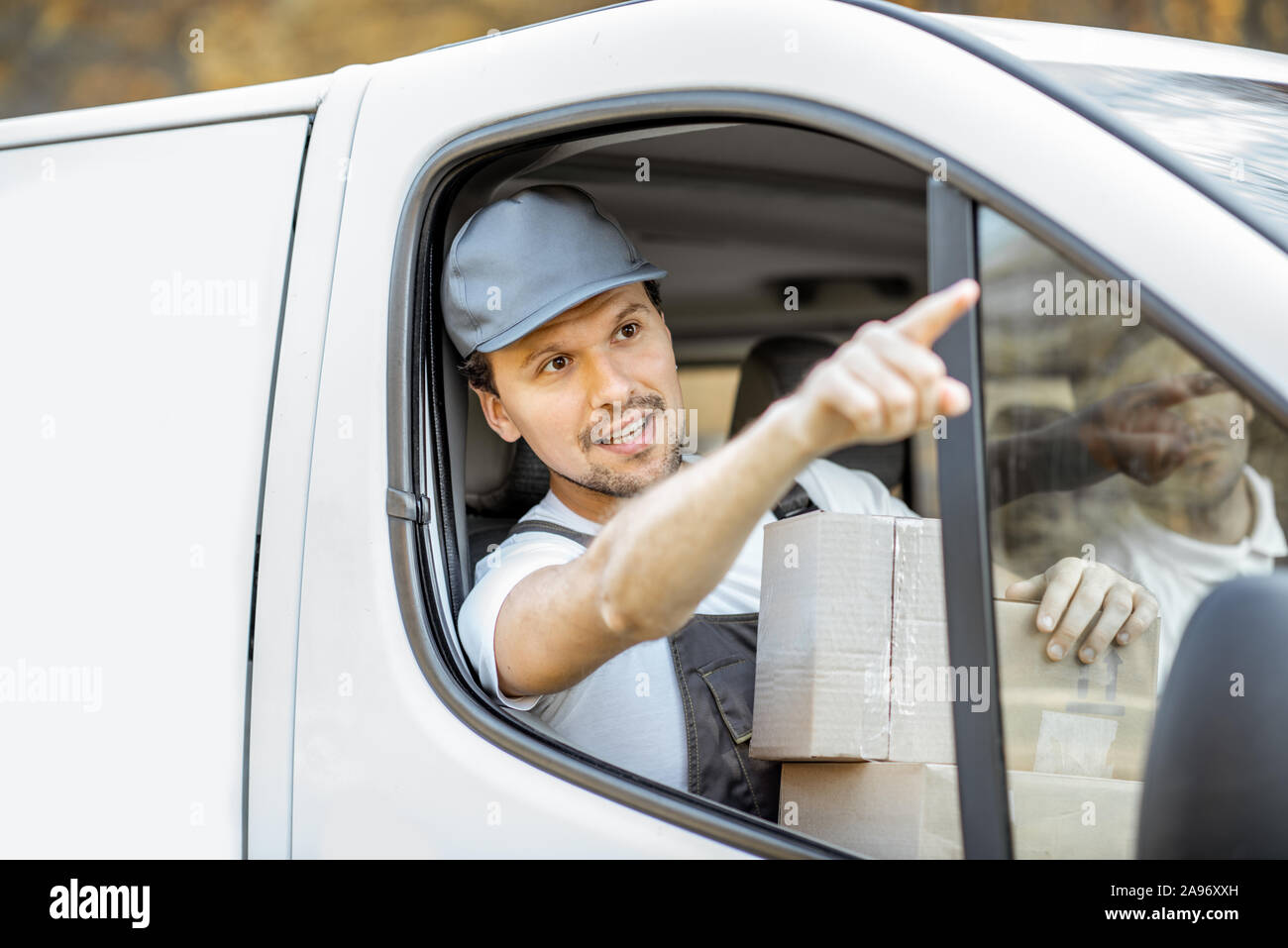 Delivery company employees driving cargo vehicle, delivering goods to ...