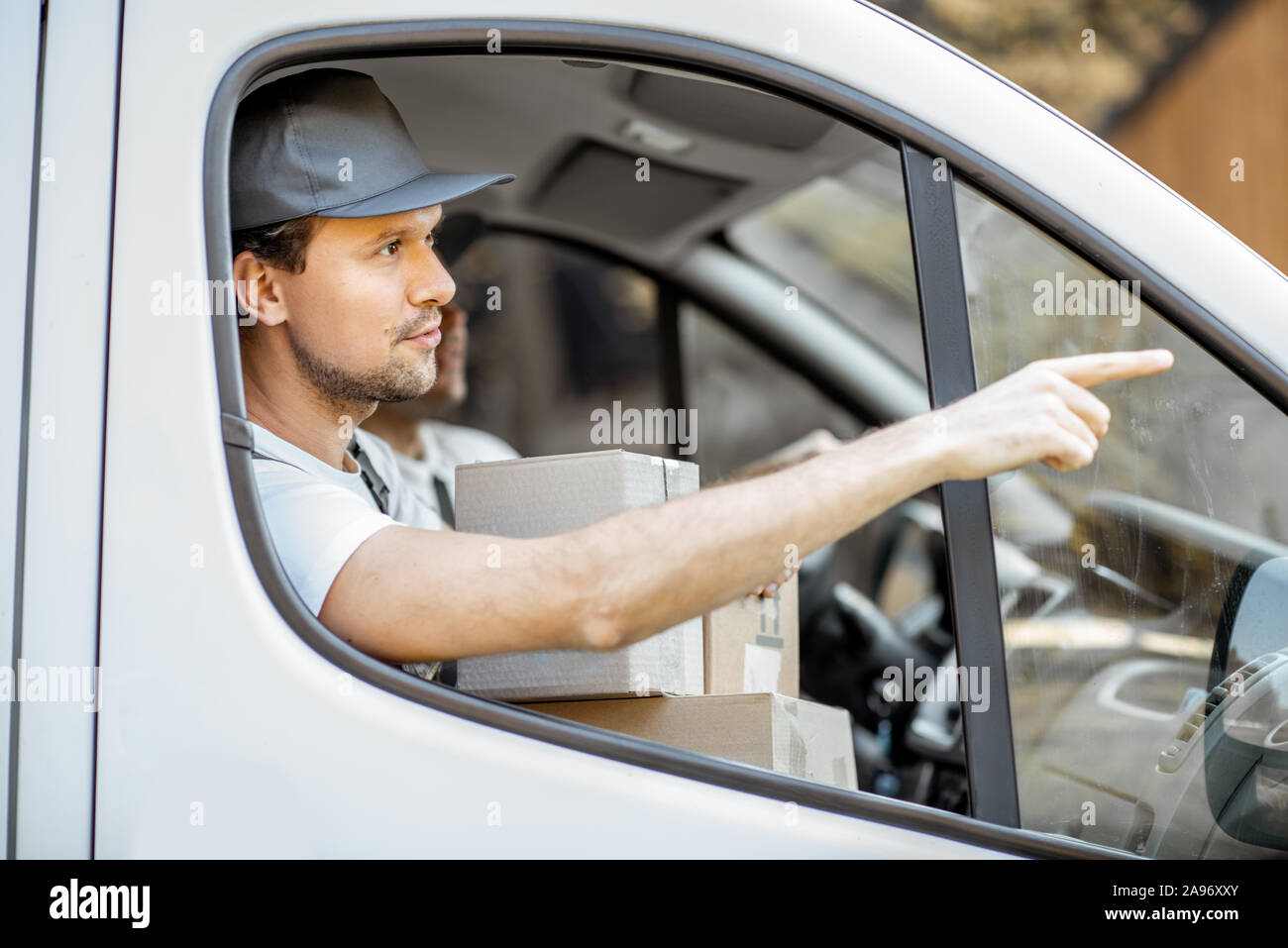 Delivery company employees driving cargo vehicle, delivering goods to ...